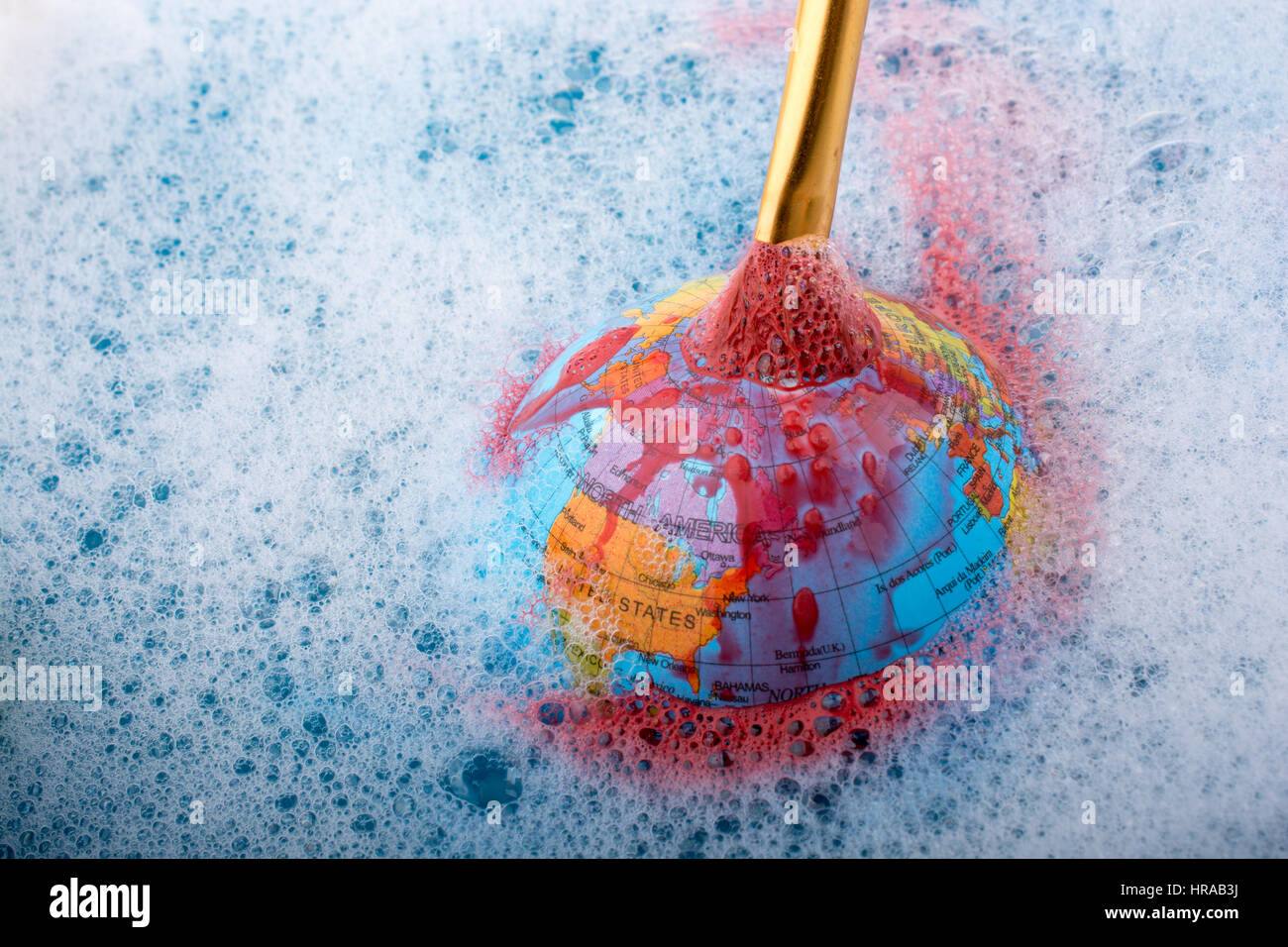 Paint dissolving through painting brush on the top of globe Stock Photo ...