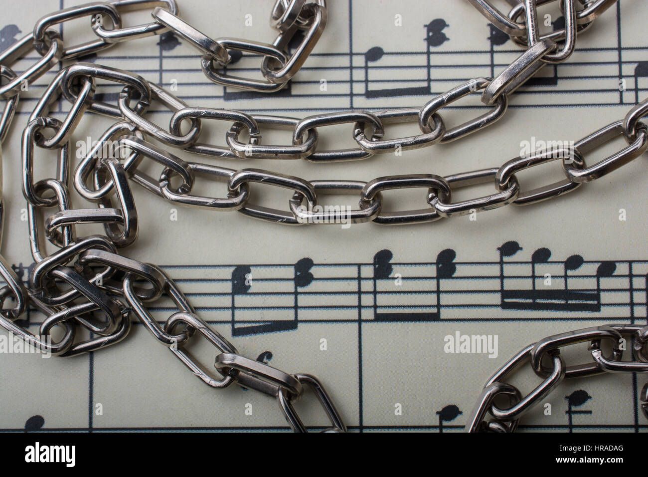Metal chain placed on a paper with musical notes Stock Photo - Alamy
