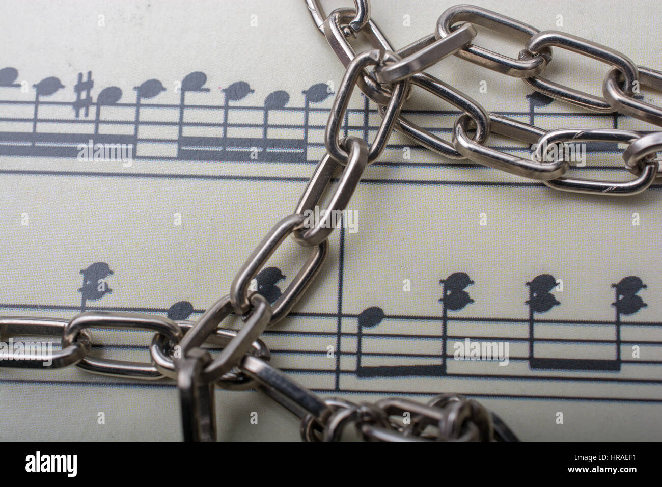 Metal chain placed on a paper with musical notes Stock Photo - Alamy