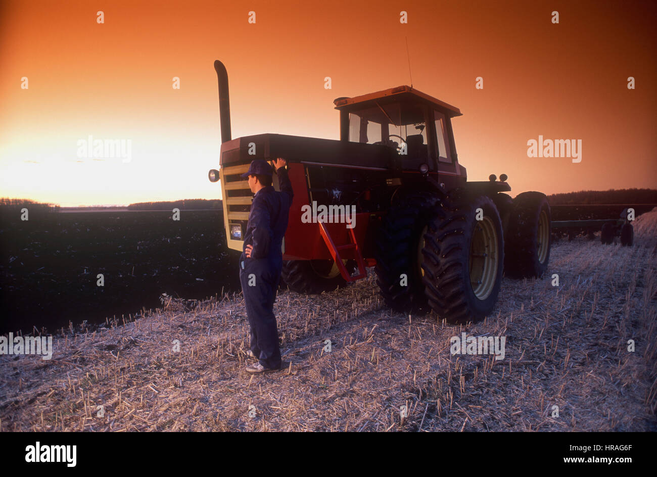 Farmer standing beside a tractor in a field Stock Photo - Alamy