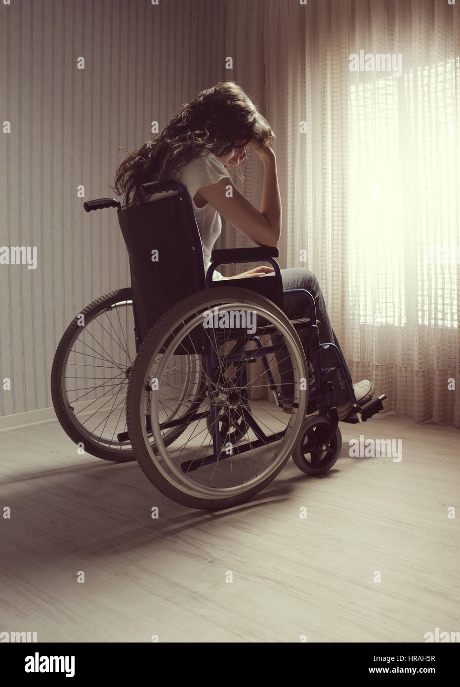Crying woman sitting in wheelchair by window Stock Photo - Alamy