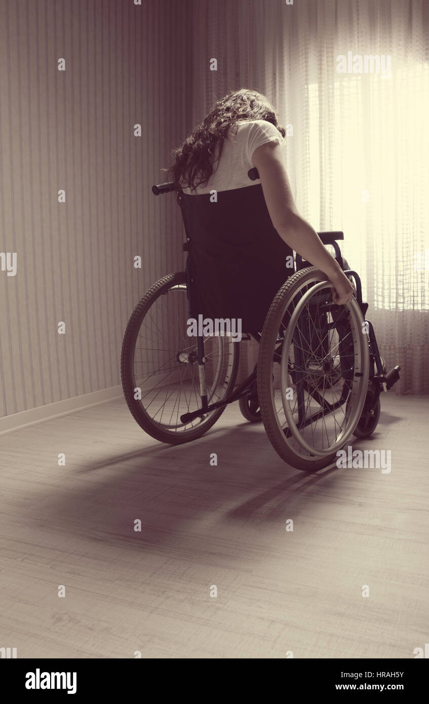 Crying woman sitting in wheelchair in front of the window Stock Photo ...