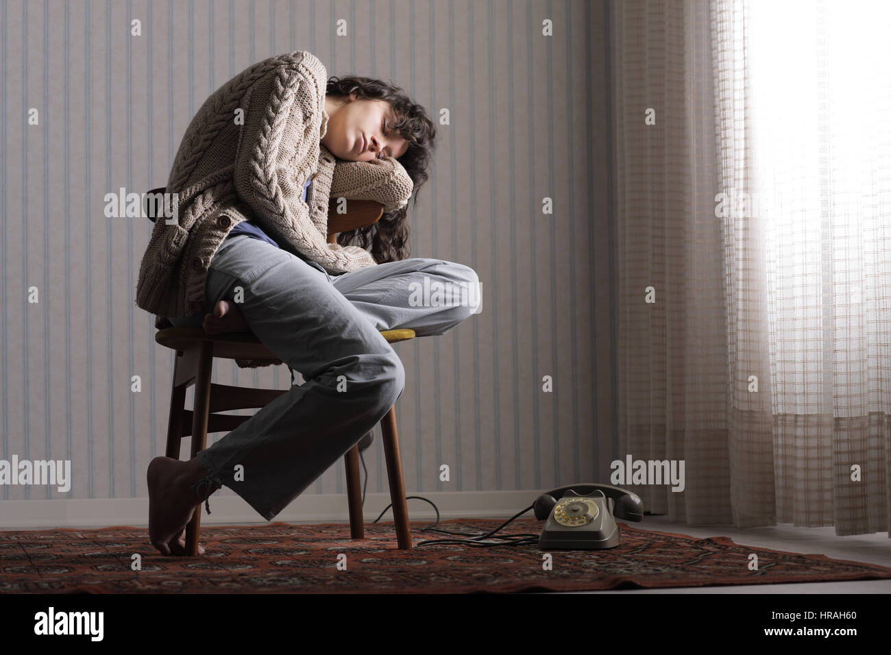 Sad woman sitting on a chair waiting for the phone call Stock Photo - Alamy