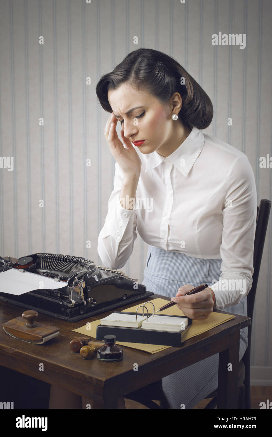 Worried woman sitting at desk in office Stock Photo - Alamy