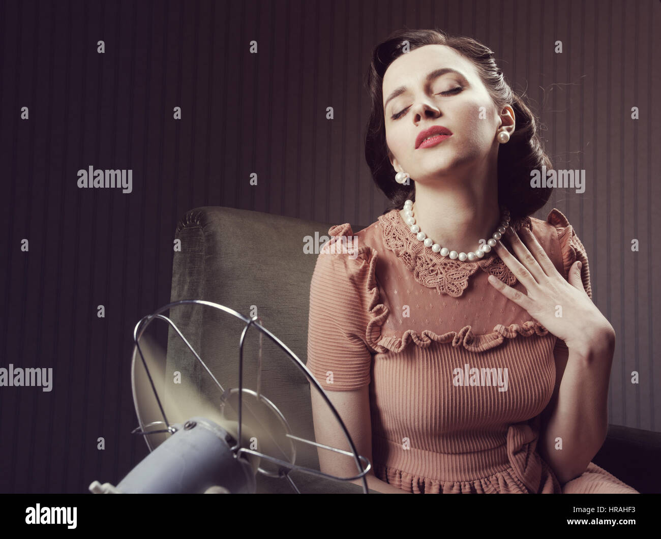 Beautiful woman using a fan to cool off Stock Photo - Alamy