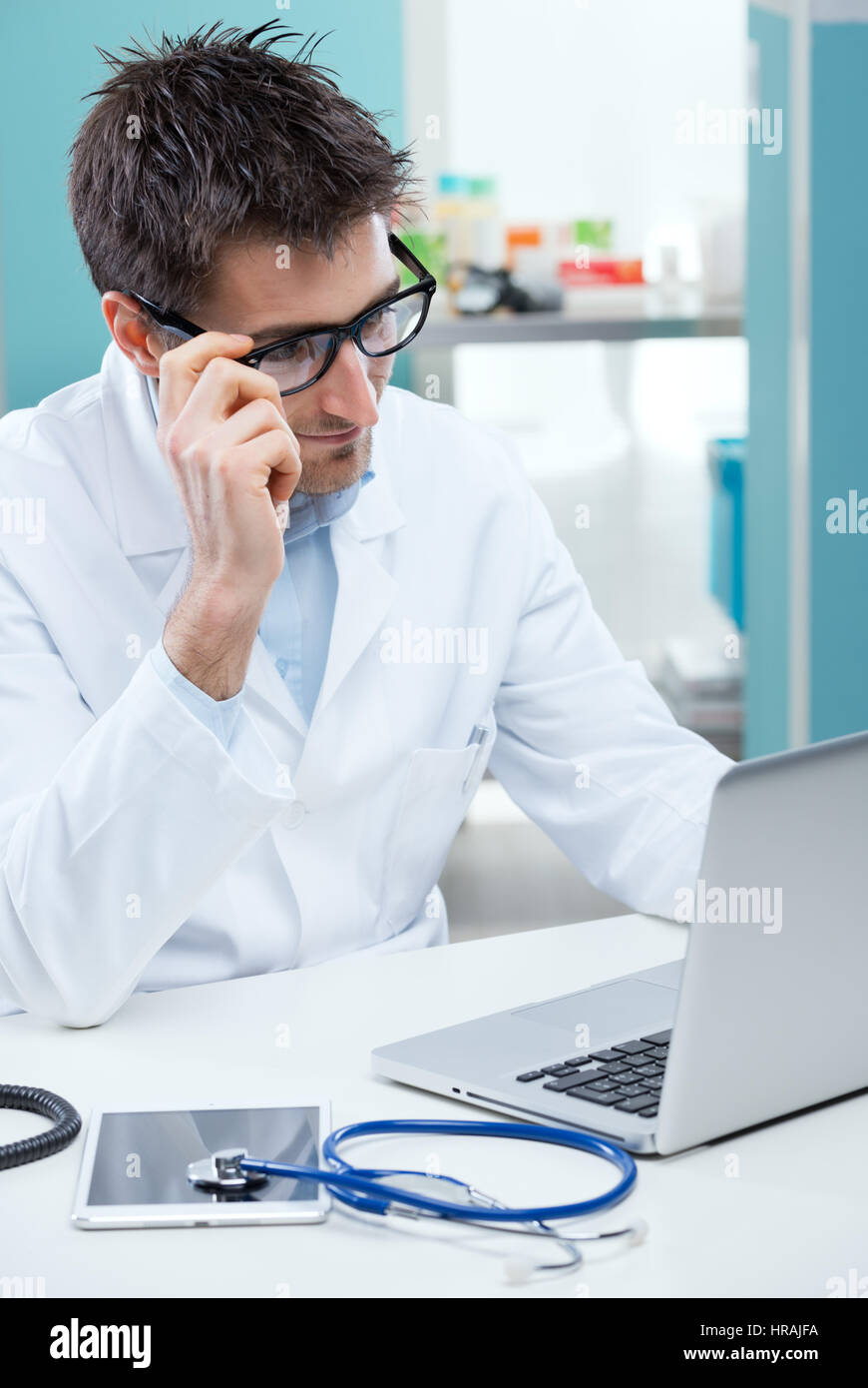 Doctor at work thinking and looking at his laptop Stock Photo - Alamy