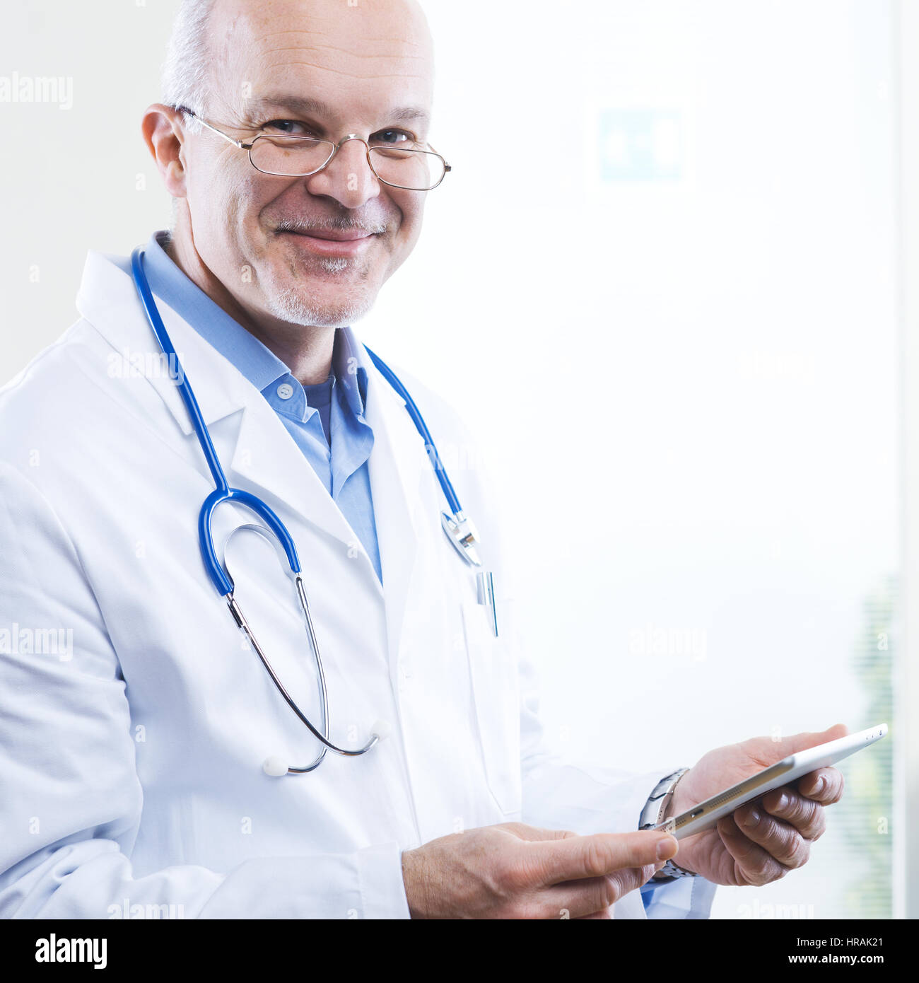 Senior friendly doctor using a tablet and smiling Stock Photo - Alamy