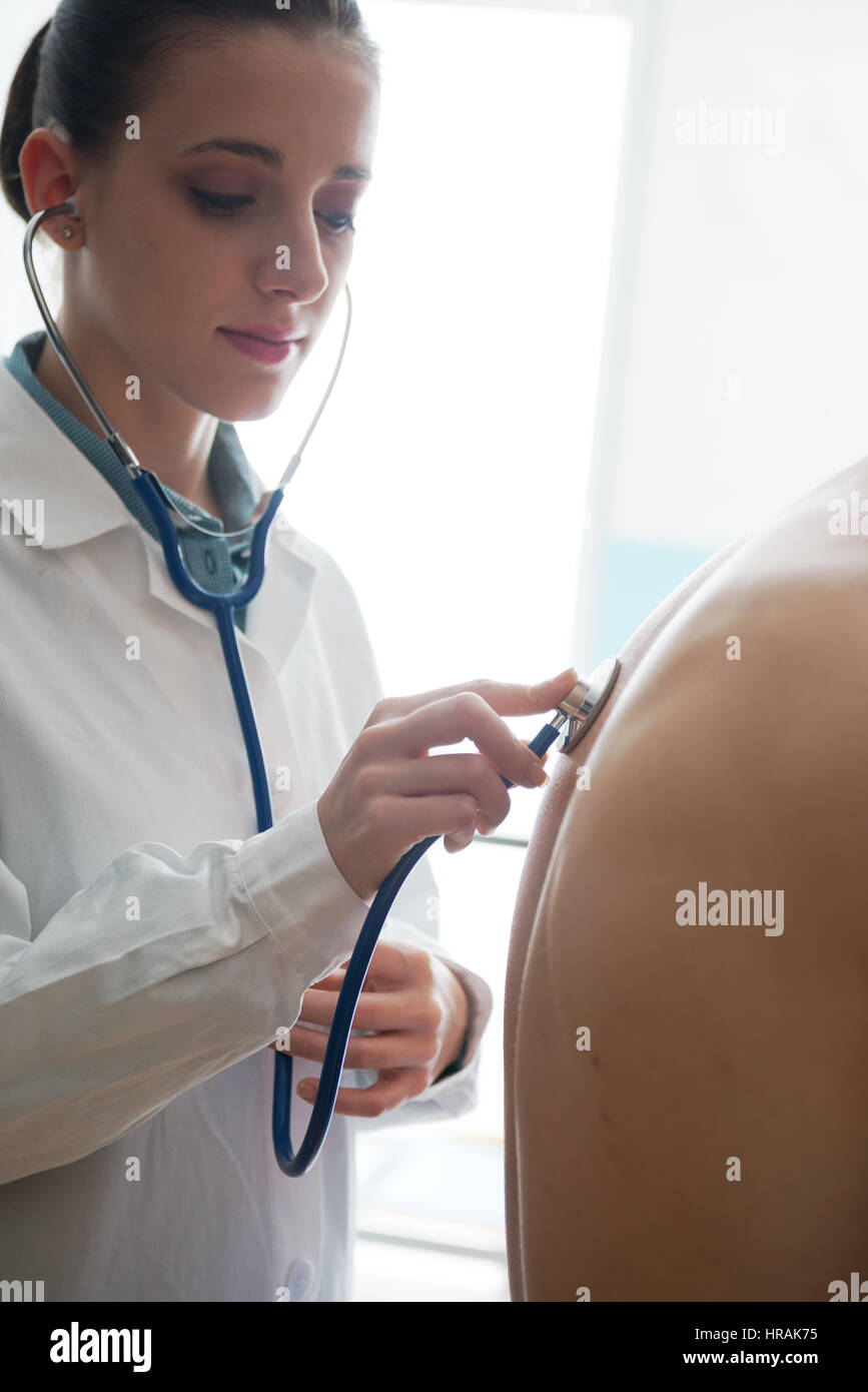 Female doctor listening man's back through stethoscope Stock Photo - Alamy