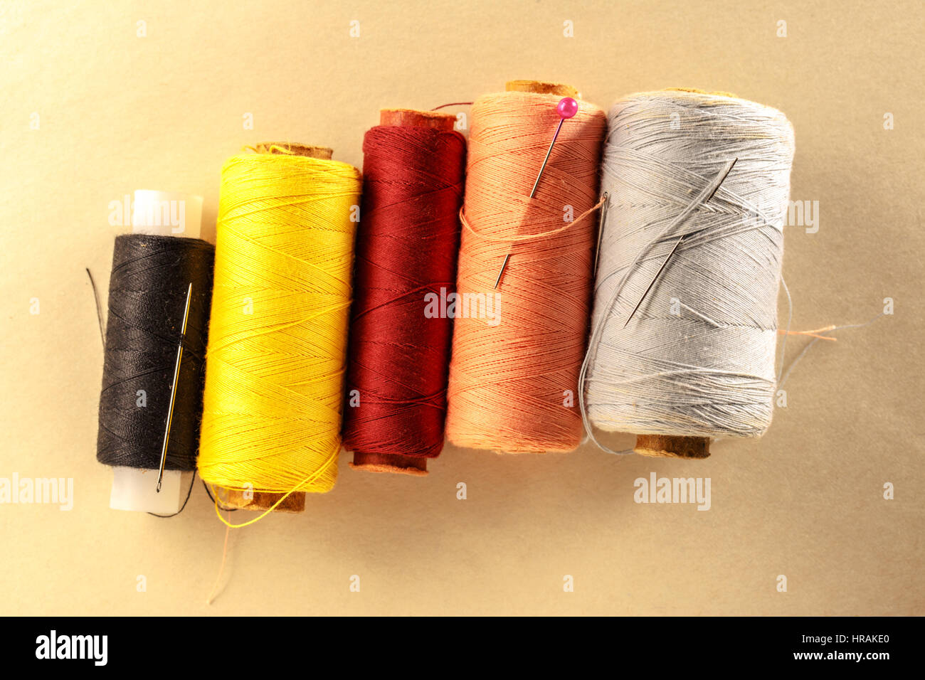 Thread bobbins and needles on paper background Stock Photo - Alamy
