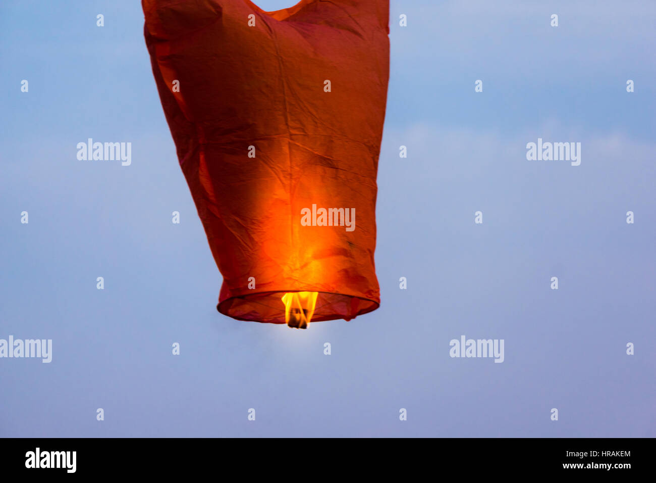 Red sky lantern flying against a blue sky with the flames showing ...
