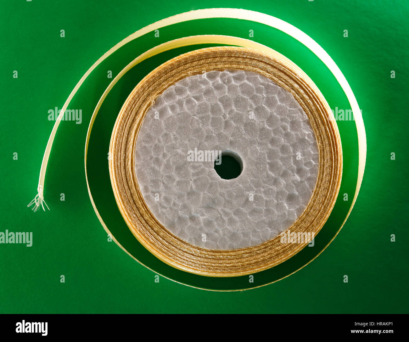 Cream ribbon in roll on green background Stock Photo - Alamy