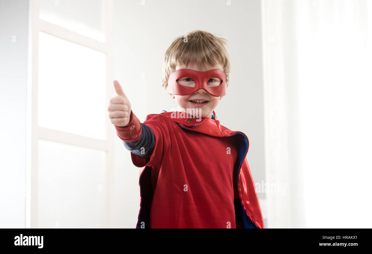 Smiling super hero kid at home with thumb up, looking at camera Stock ...