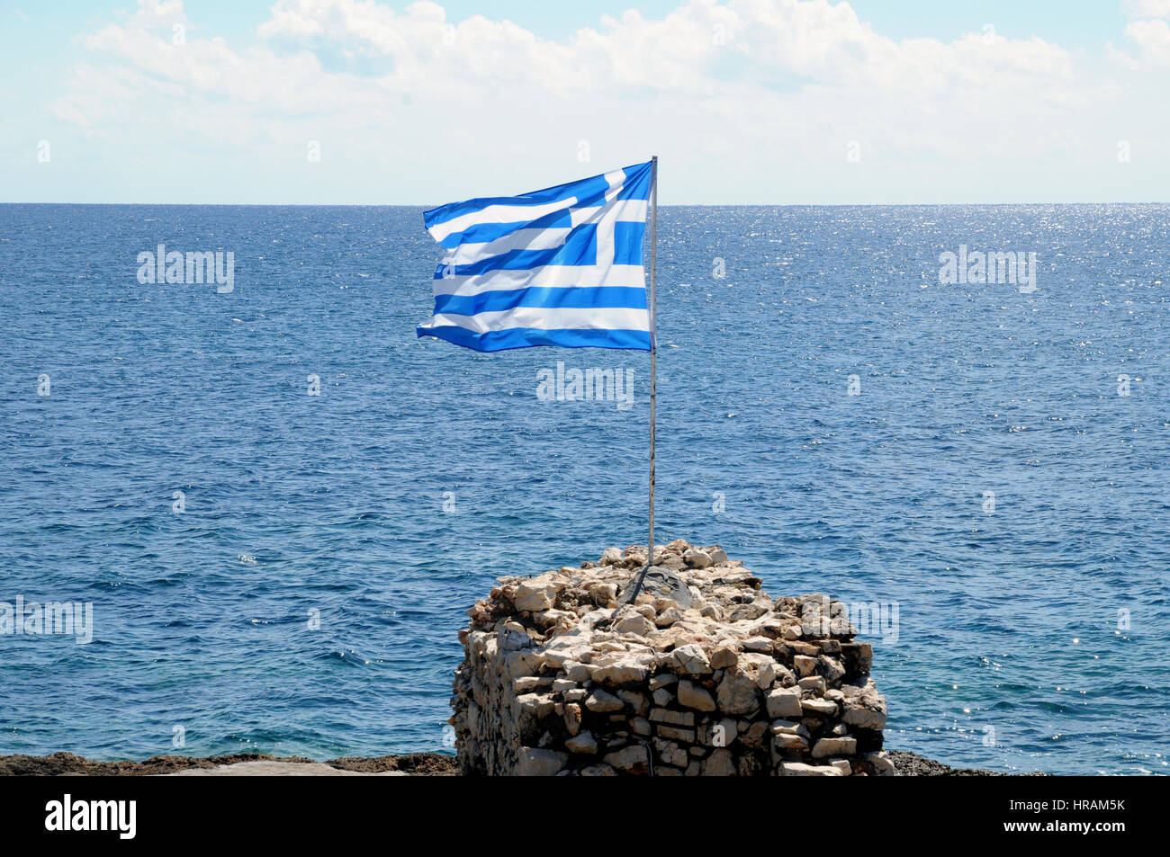 The Greek flag flying on a rock just off shore from the Peloponessean ...