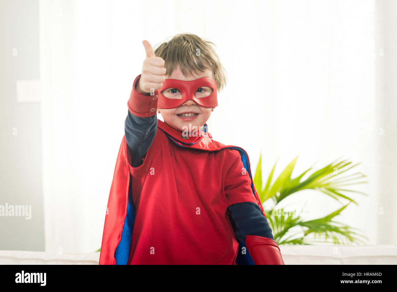 Smiling super hero kid at home with thumb up, looking at camera Stock ...