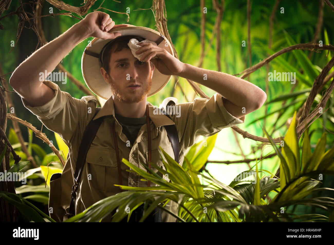 Tired young explorer in the jungle wiping sweat off his forehead Stock ...