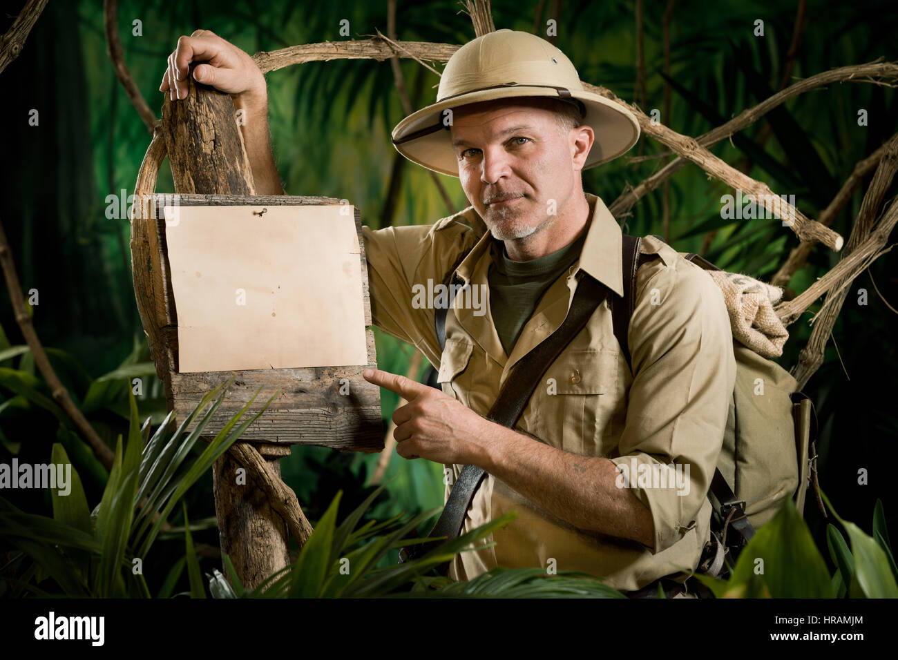 Explorer pointing to a sign looking at camera Stock Photo - Alamy