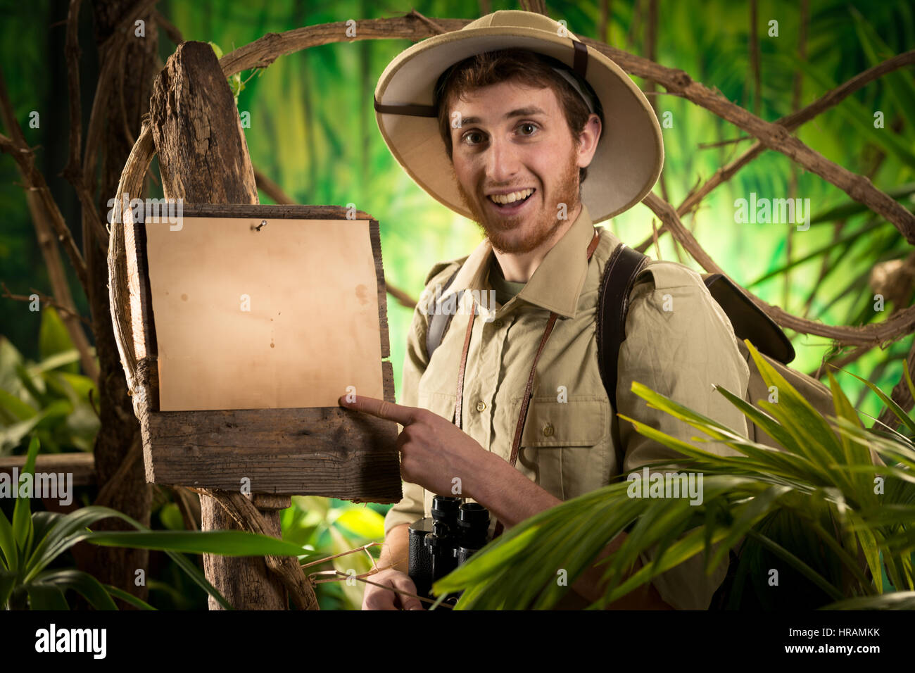 Cheerful young explorer pointing to an information sign in the forest ...