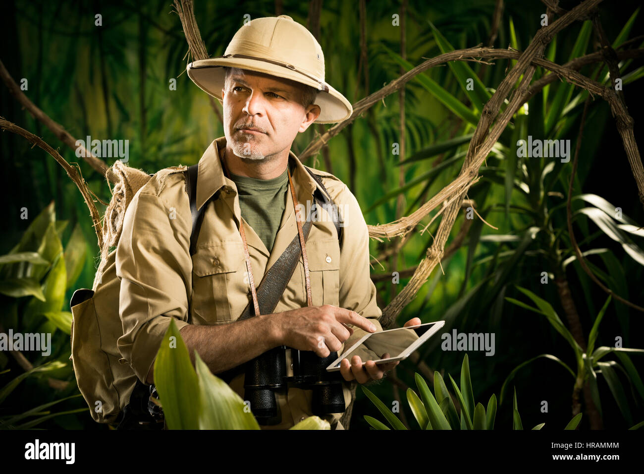 Colonial style adventurer with digital tablet exploring jungle ...