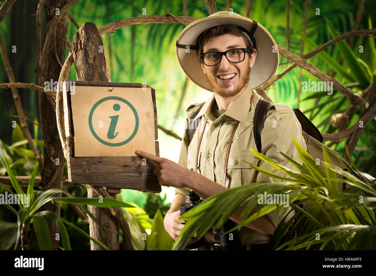 Cheerful young explorer pointing to an information sign in the forest ...