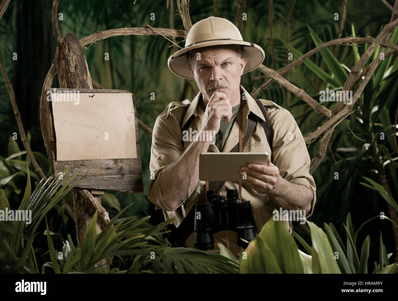 Colonial style adventurer with digital tablet exploring jungle ...