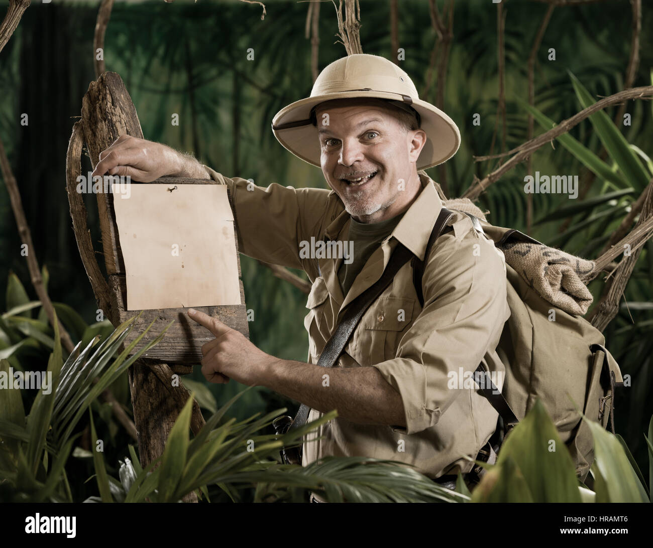 Cheerful explorer pointing to a sign looking at camera Stock Photo - Alamy