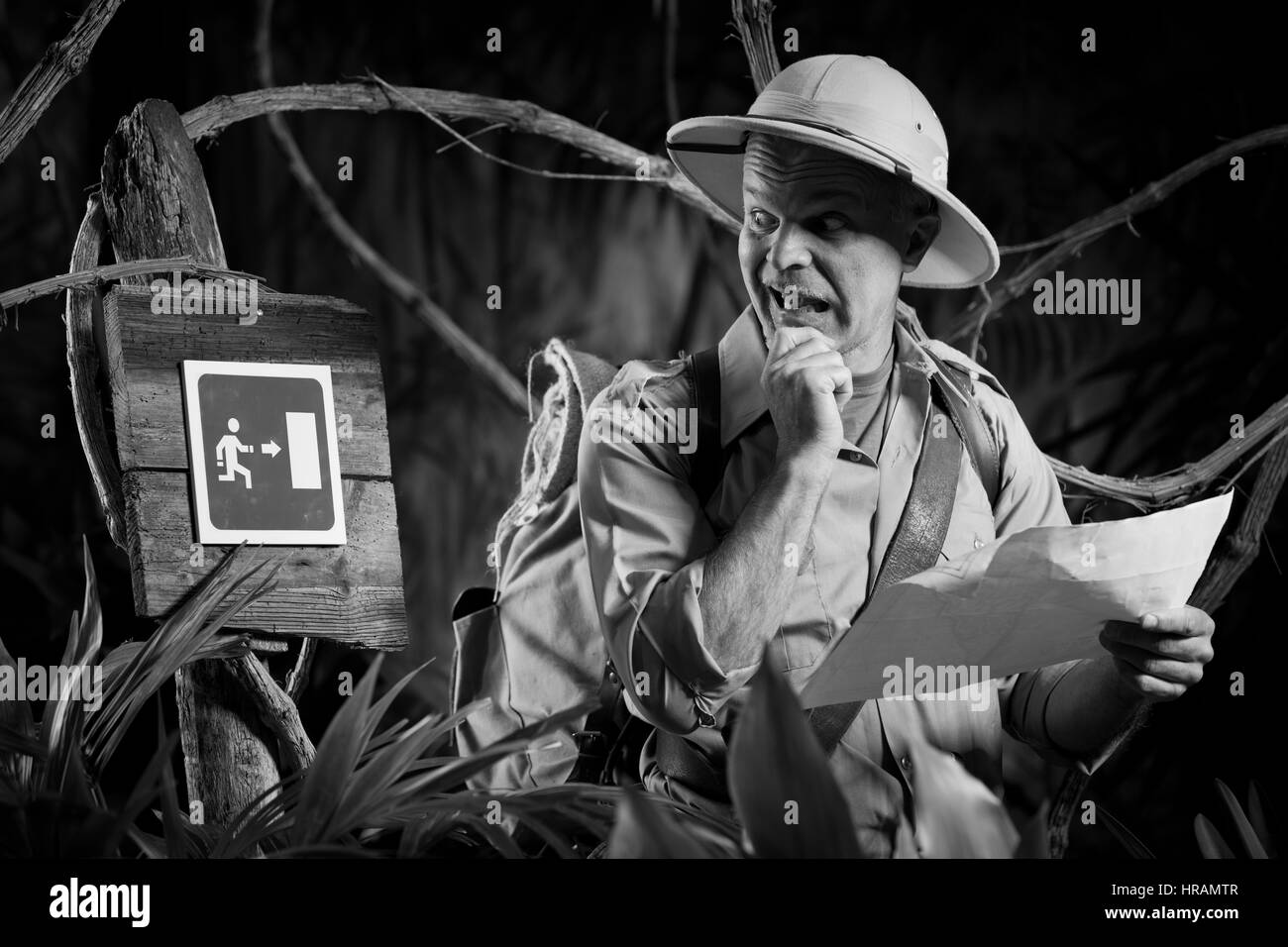 Surprised explorer holding a map and finding an exit sign in the jungle ...