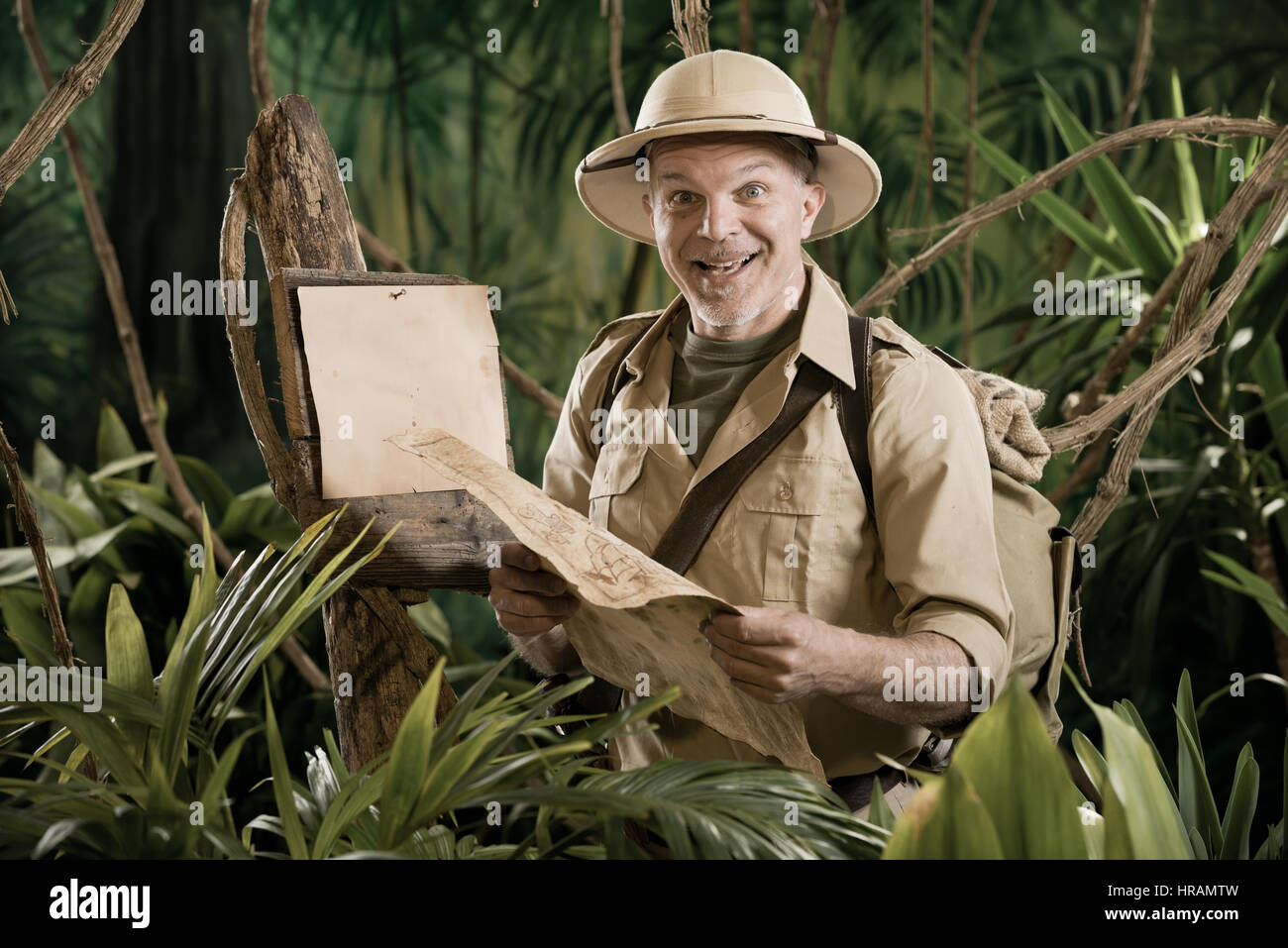 Cheerful vintage explorer in the jungle with map and blank sign Stock ...