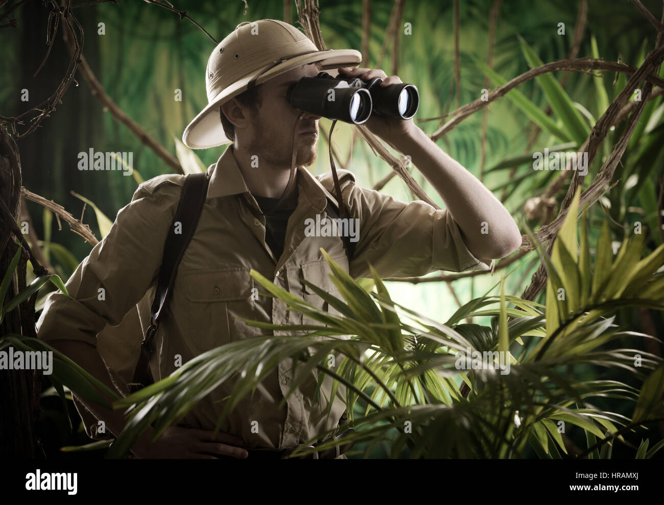 Expert explorer in the jungle looking away through binoculars Stock ...
