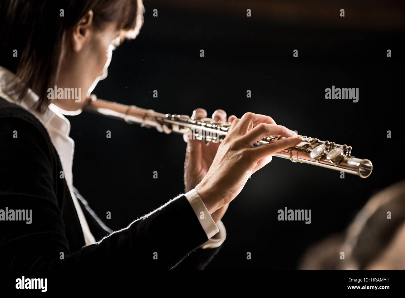 Elegant female flutist playing flute on dark background Stock Photo - Alamy