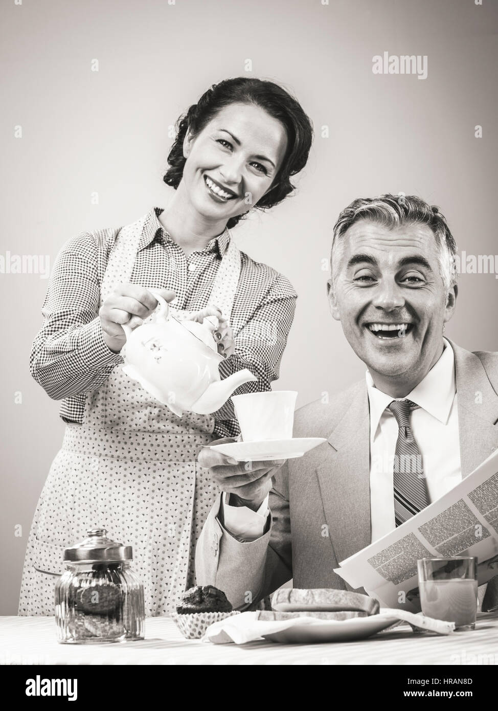 1950s beautiful woman serving tea for breakfast to her smiling husband ...
