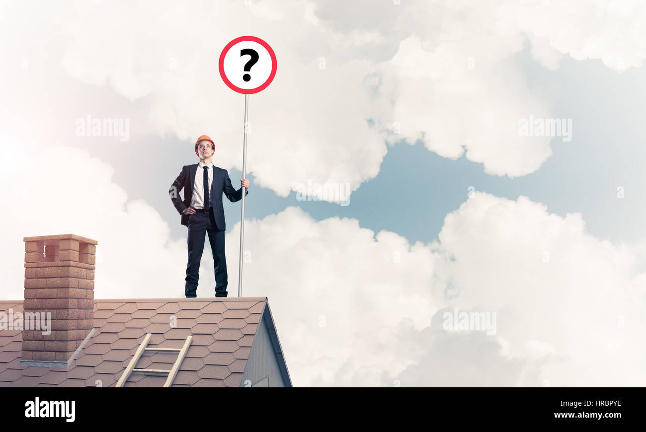 Businessman on brick house roof showing banner with question mar Stock ...