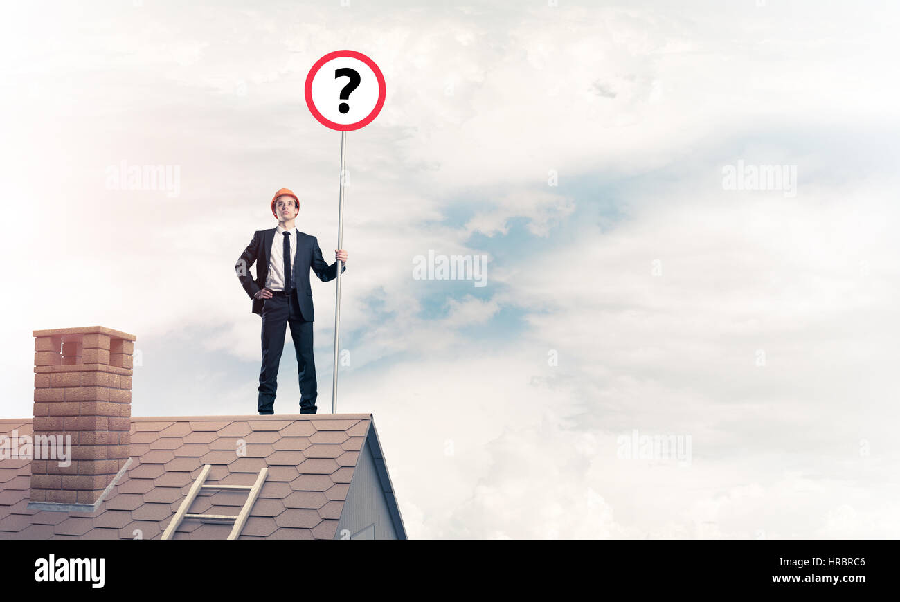 Businessman on brick house roof showing banner with question mar Stock ...