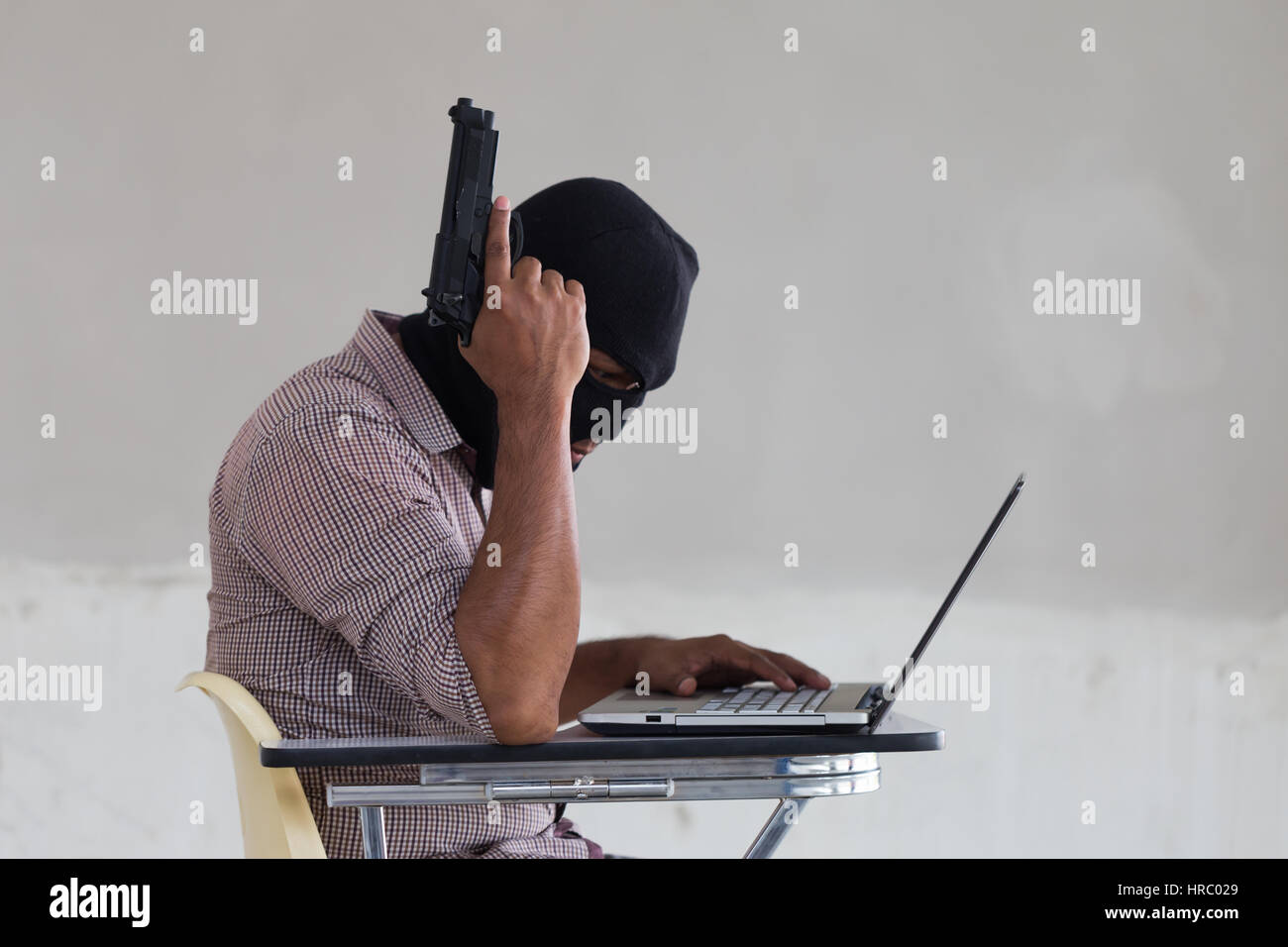 Robber with a gun and a computer Stock Photo - Alamy