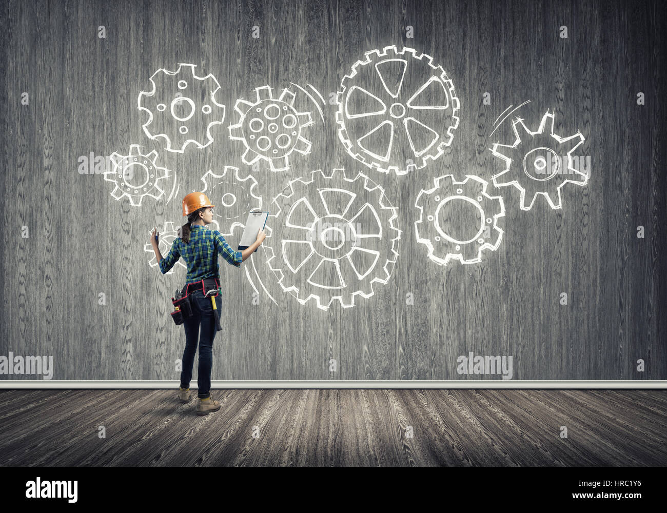 Back view of engineer woman in hardhat and sketched concept of teamwork ...