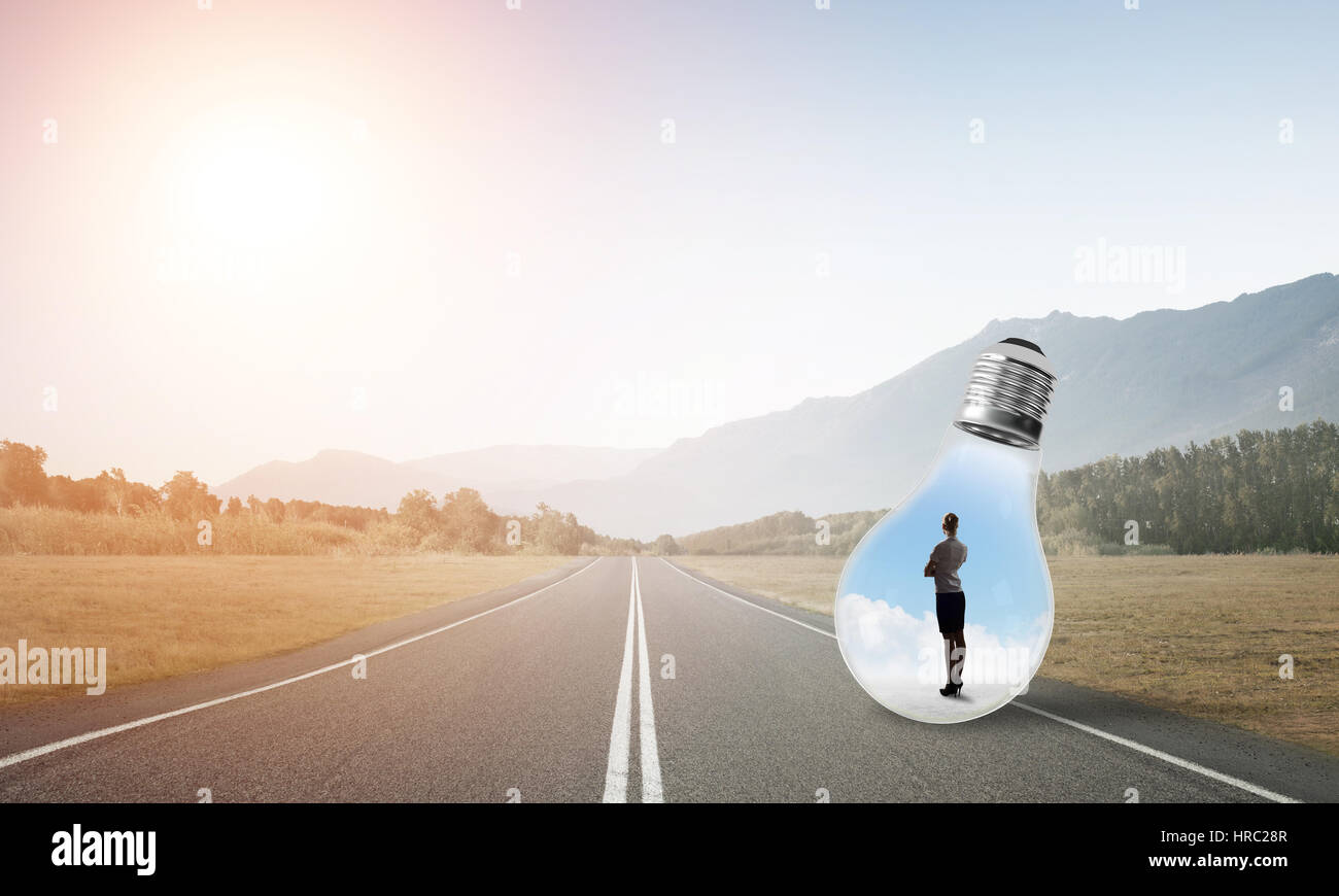 Young businesswoman trapped inside of light bulb on asphalt road Stock ...