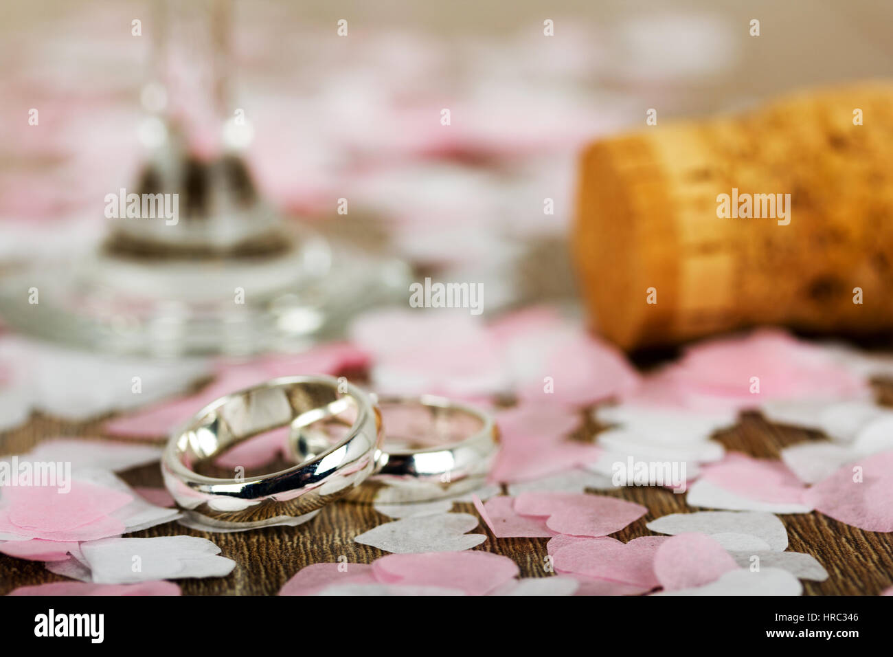 pair of white gold wedding rings on a wooden background with confetti ...