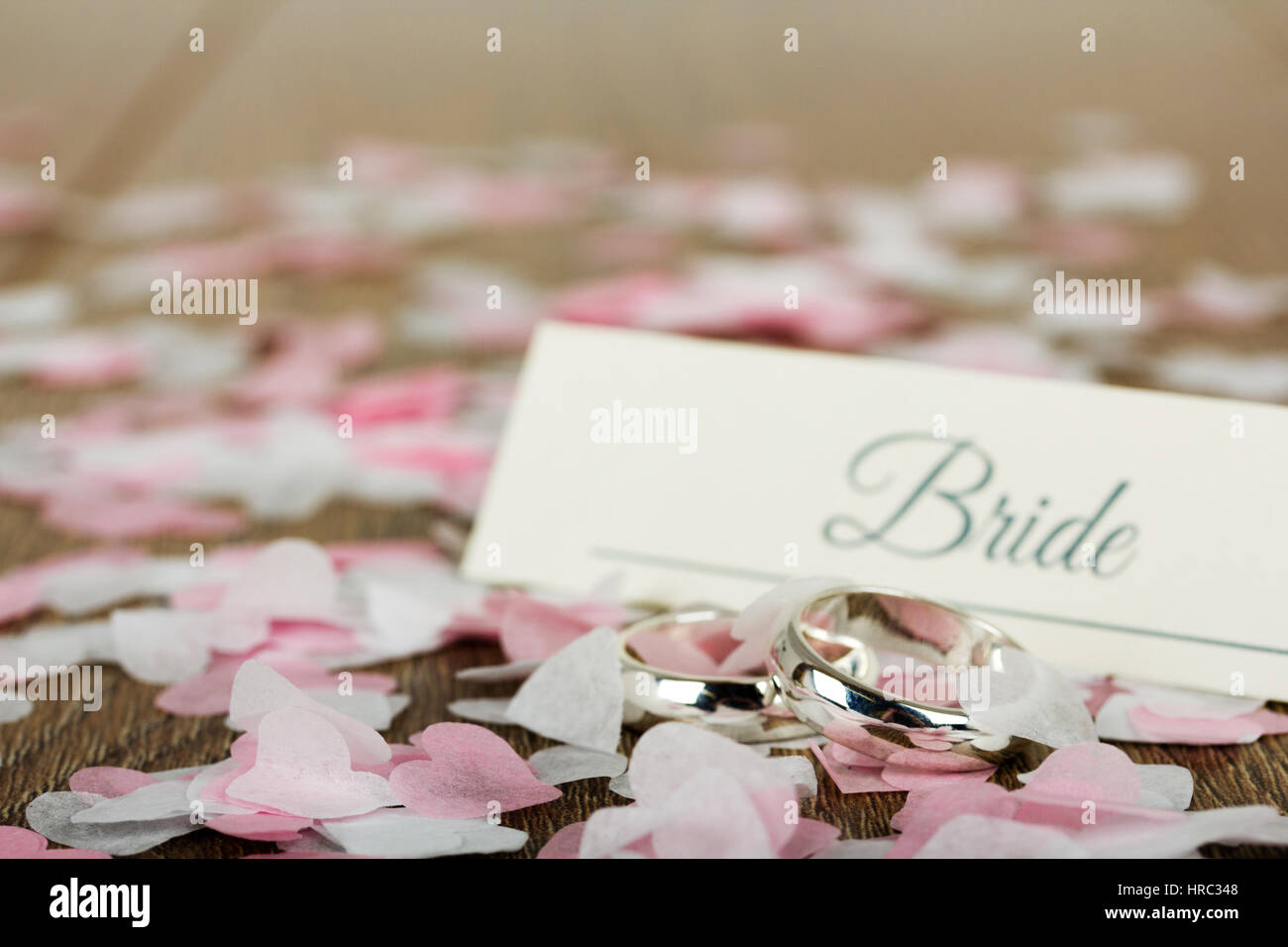 pair of white gold wedding rings on a wooden background with confetti ...
