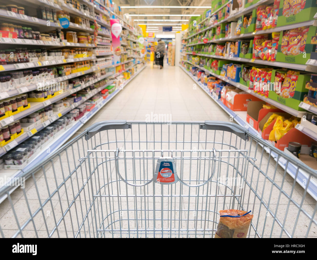 Shopping cart in alley of supermarket, blurred shelf Stock Photo - Alamy