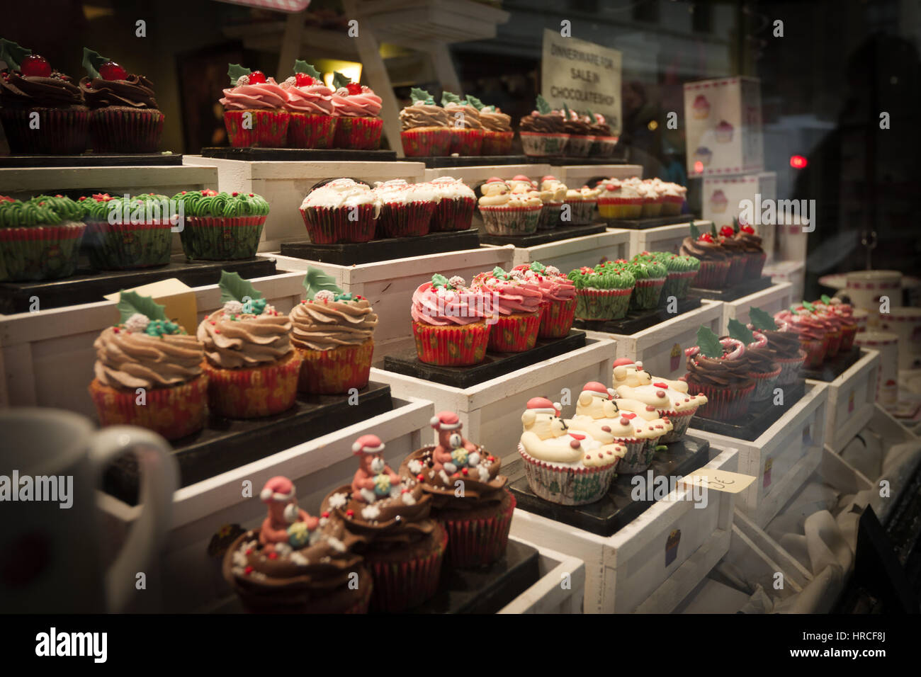Display of colorful iced muffins with festive decorations in a bakery ...