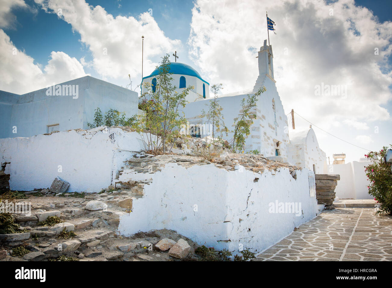 Old church in village with white crumbling walls, blue dome and flag of ...