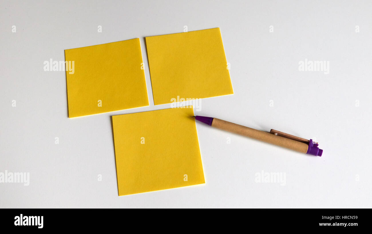 Three yellow notes on a white table Stock Photo - Alamy