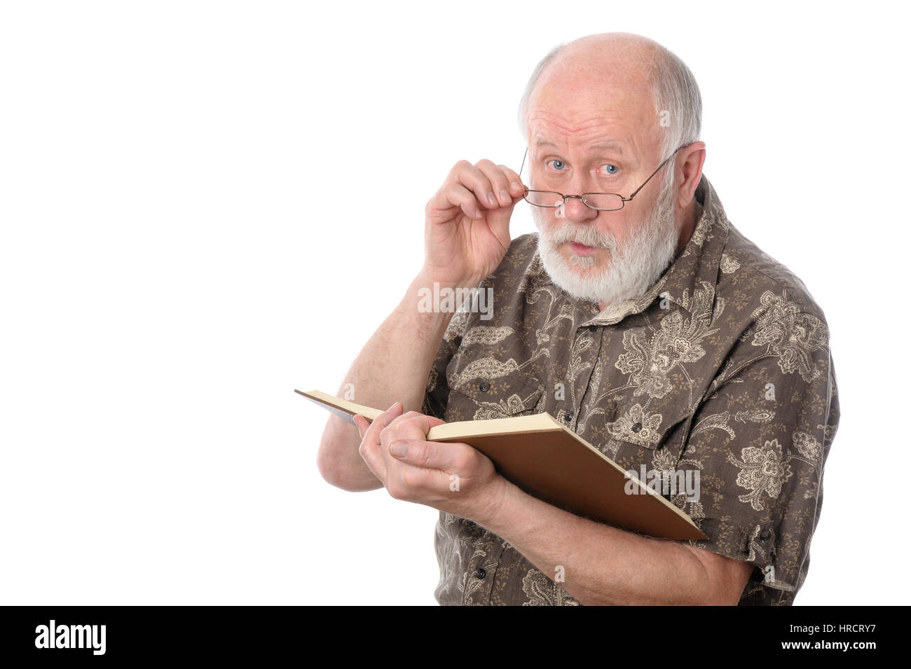 Handsome bald and bearded senior man looking over glasses when reading ...
