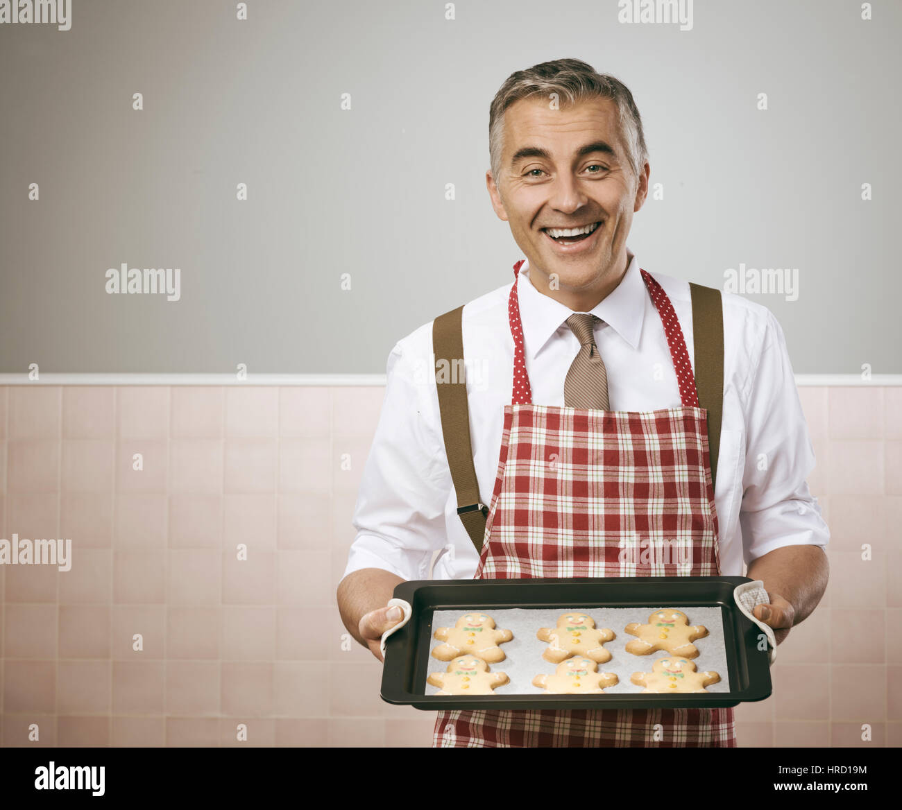 Smiling vintage man in apron cooking delicious gingerbread men cookies ...