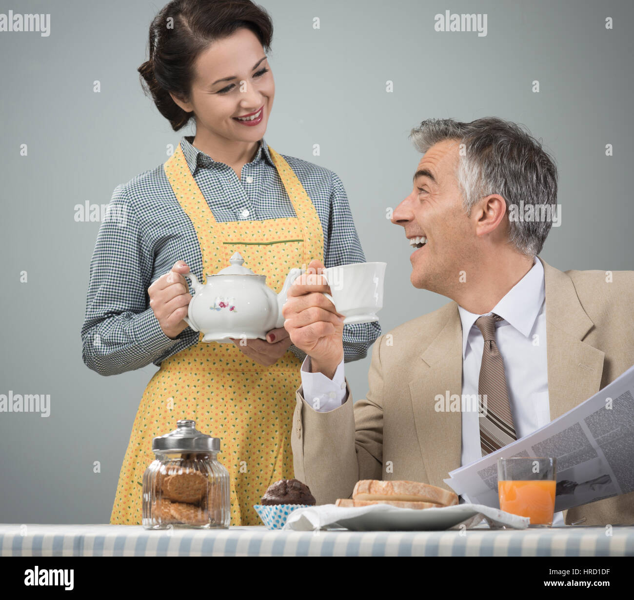 1950s beautiful woman serving tea for breakfast to her smiling husband ...