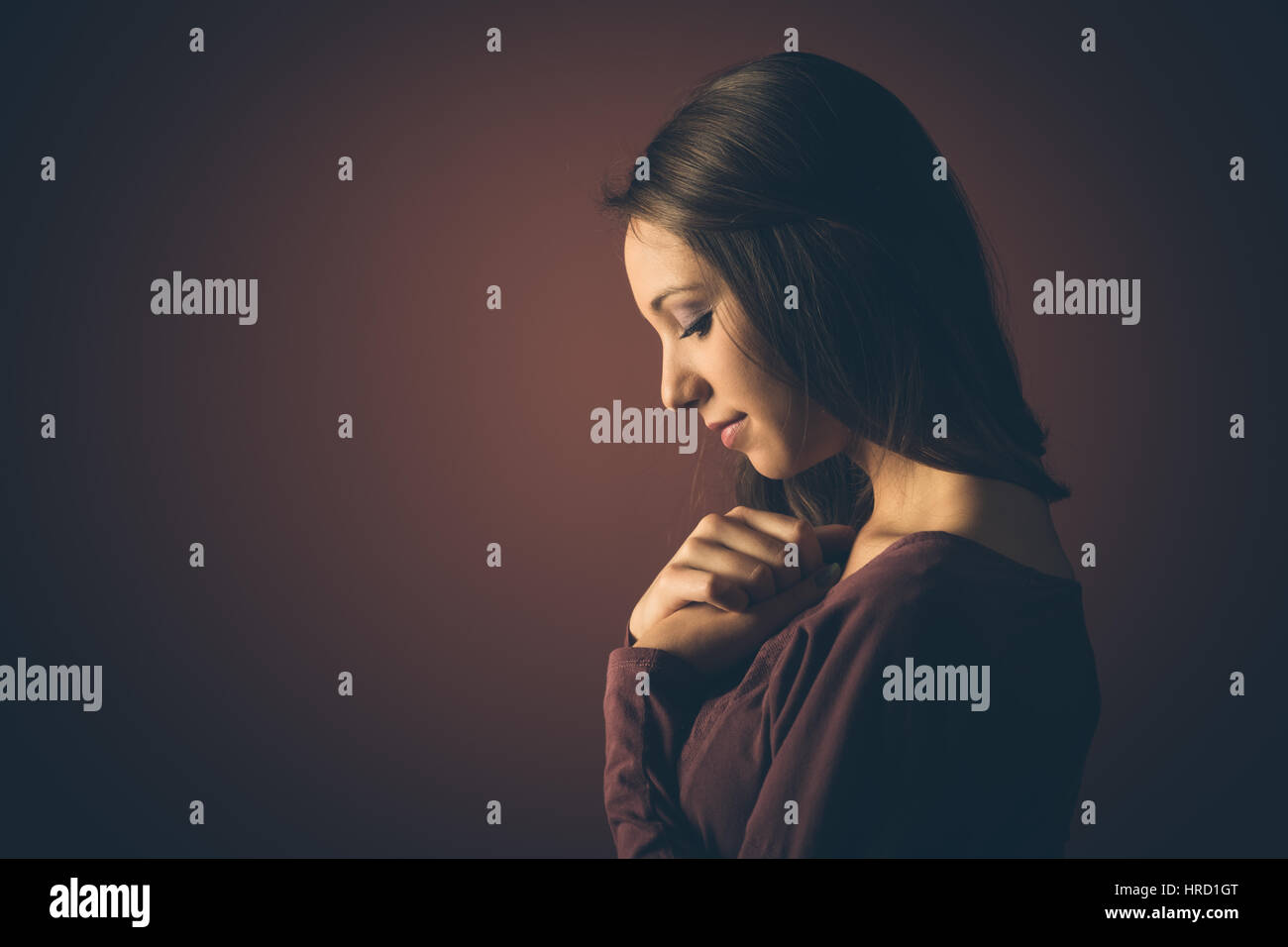 Beautiful young woman looking down, profile on dark background Stock ...