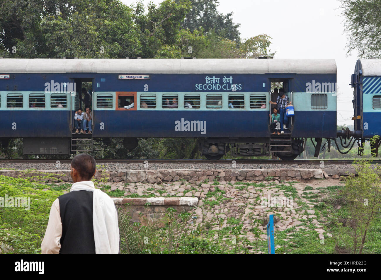 A long distance passenger train slows approaching a rural road crossing ...
