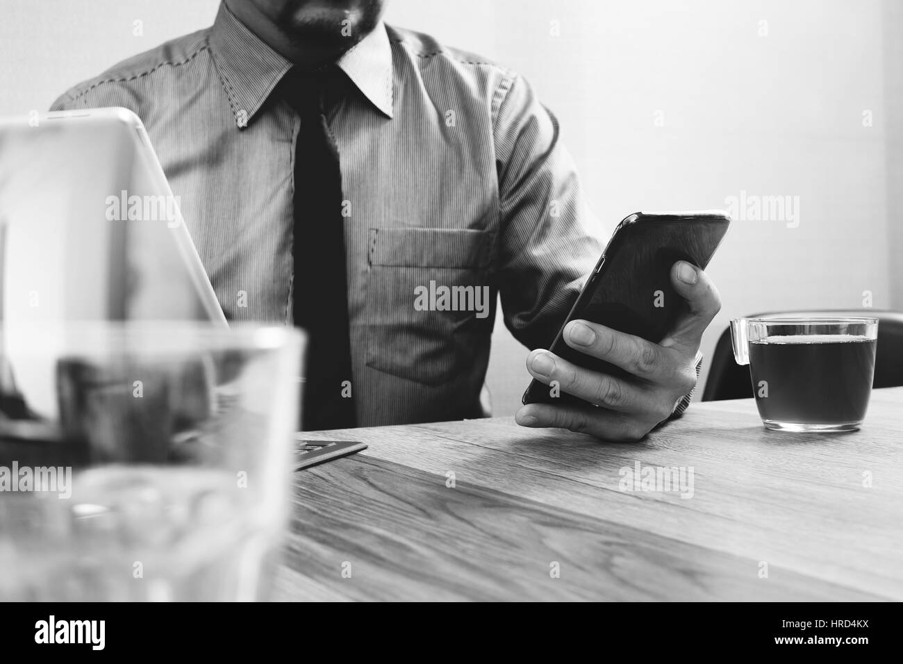success businessman hand using smart phone,digital tablet docking smart keyboard,coffee cup on ...