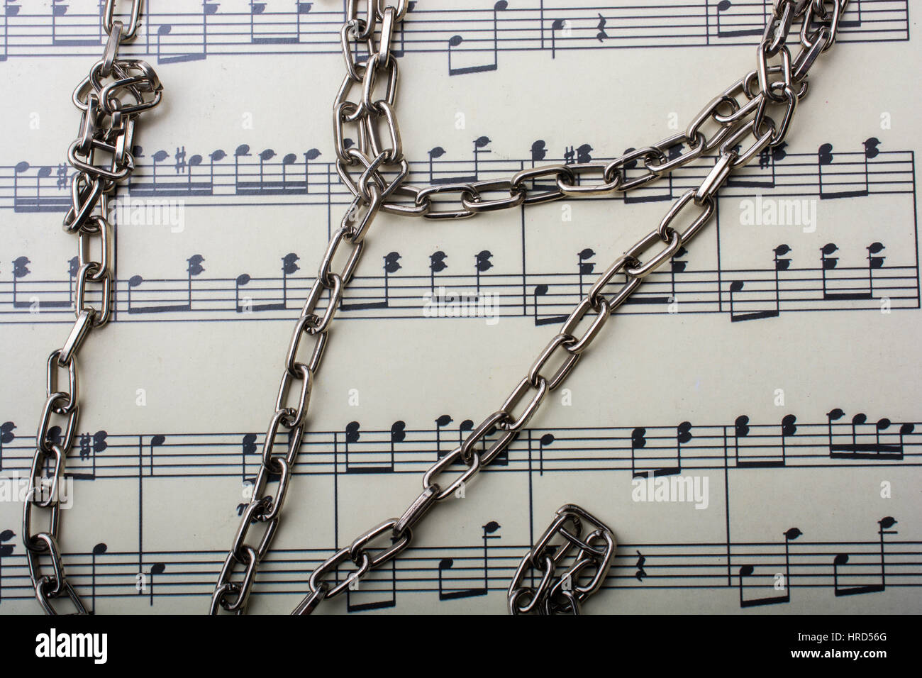 Metal chain placed on a paper with musical notes Stock Photo - Alamy
