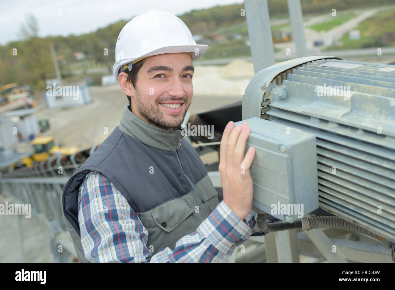 Workman next to mechanical elevator Stock Photo - Alamy
