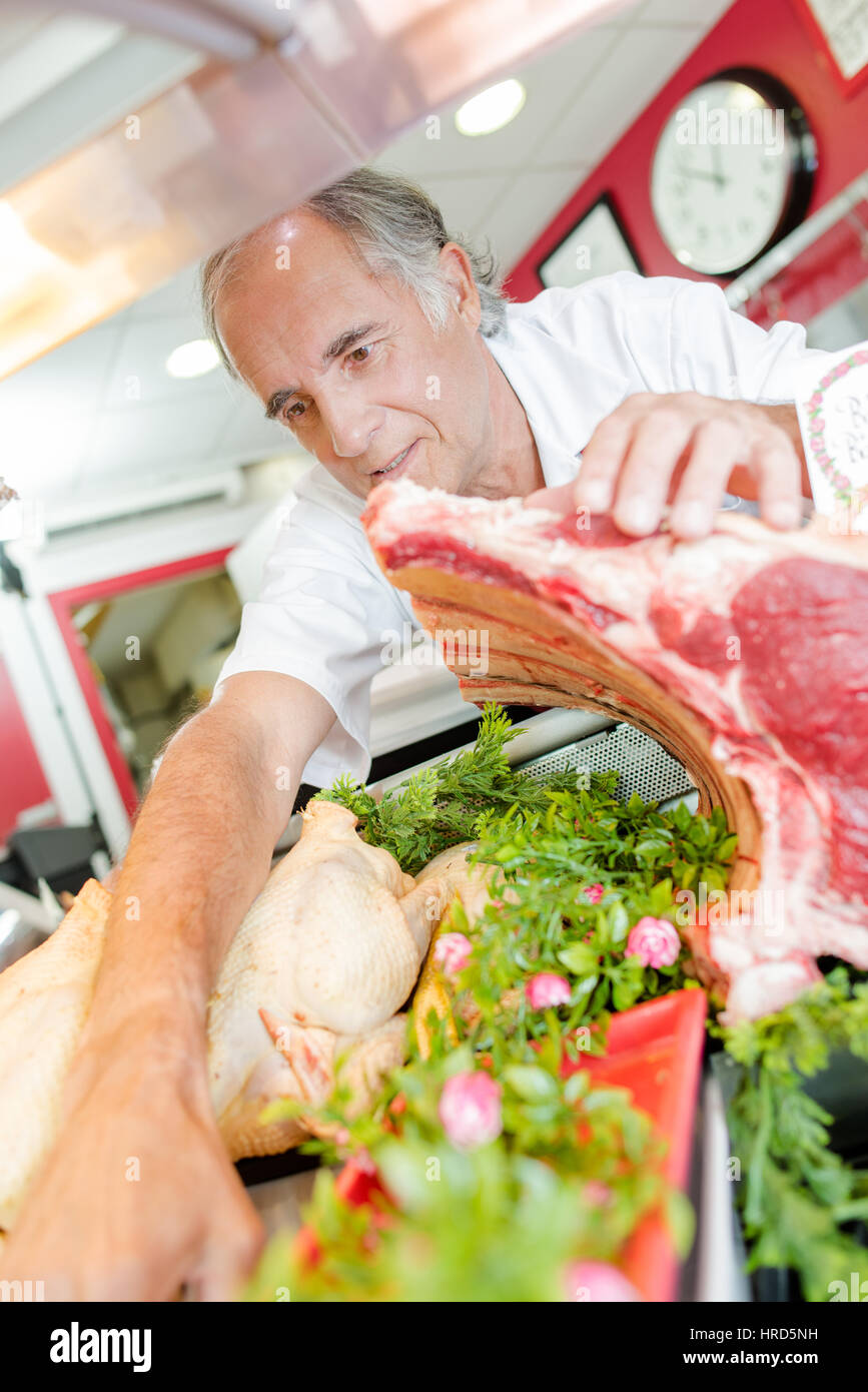 Butcher reaching into counter Stock Photo - Alamy